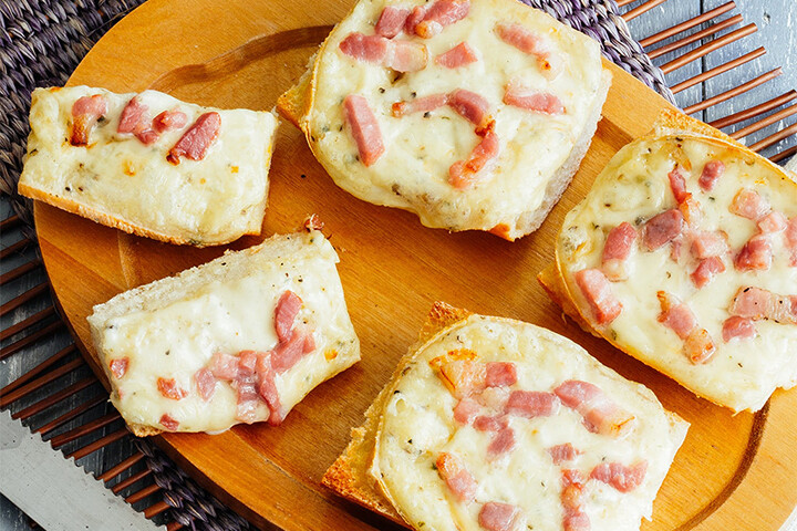 Tostadas de pan con queso Raclette y tocino. Receta de botana